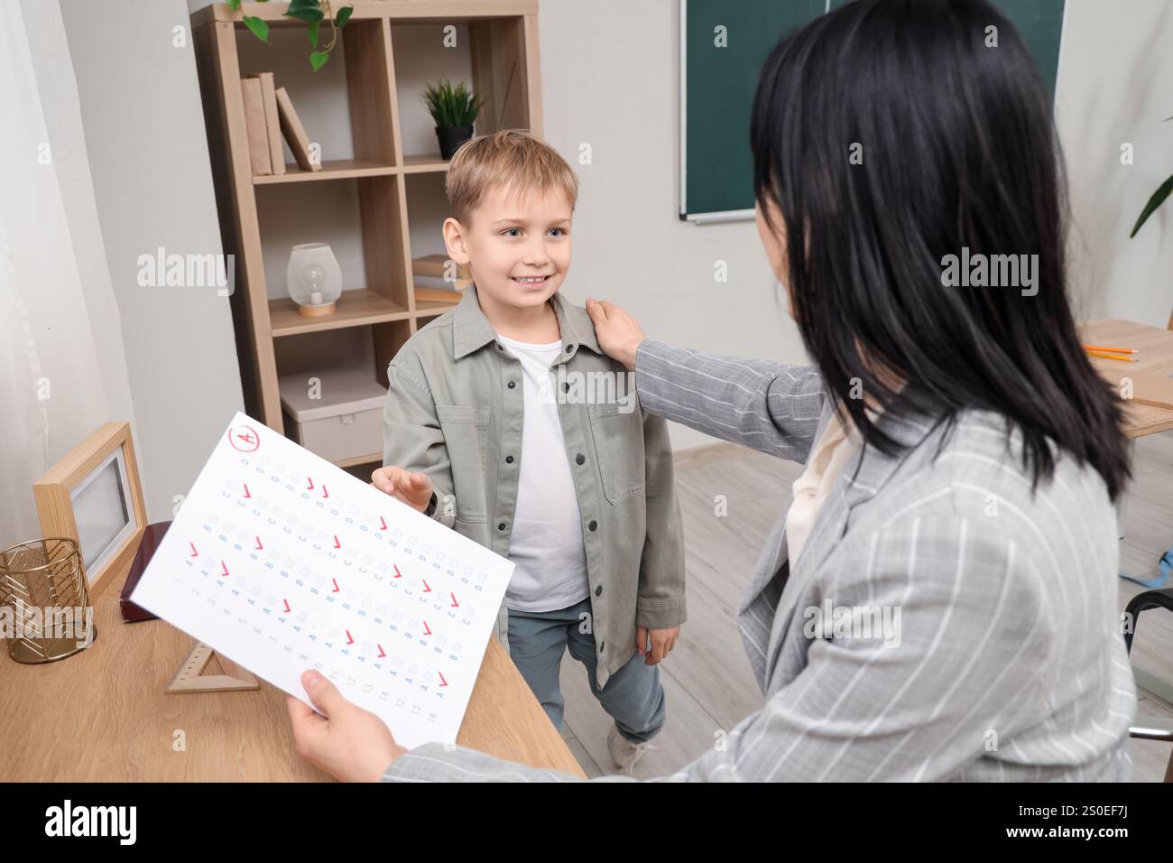 Cute schoolboy receiving answer sheet with A grade from teacher in ...