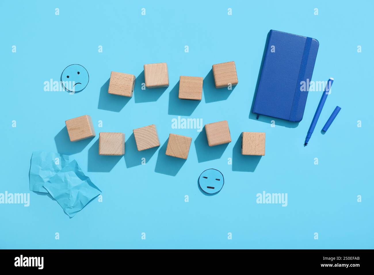 Cubes with notebook and drawn sad faces on blue background Stock Photo ...