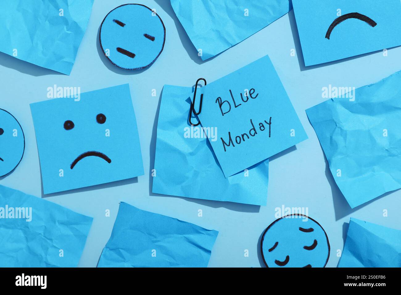 Paper sheets with drawn sad faces and text BLUE MONDAY Stock Photo - Alamy