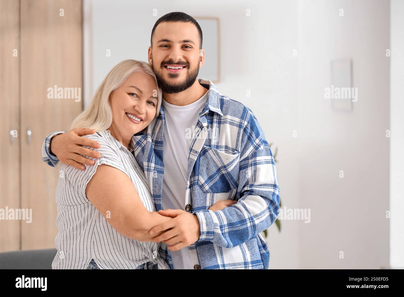 Happy young man hugging his mother at home Stock Photo - Alamy
