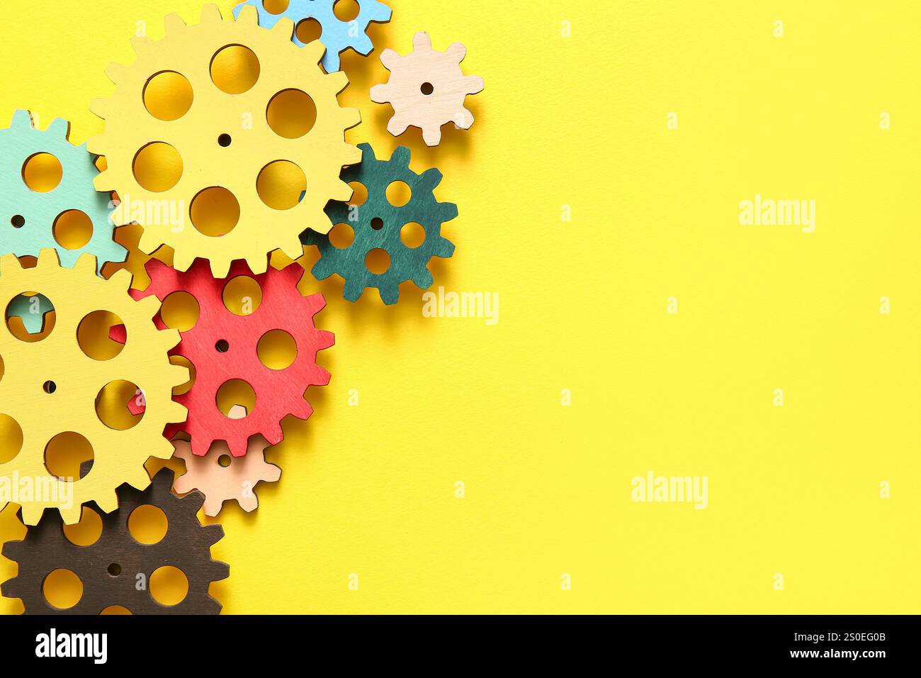 Wooden gears on yellow background Stock Photo - Alamy