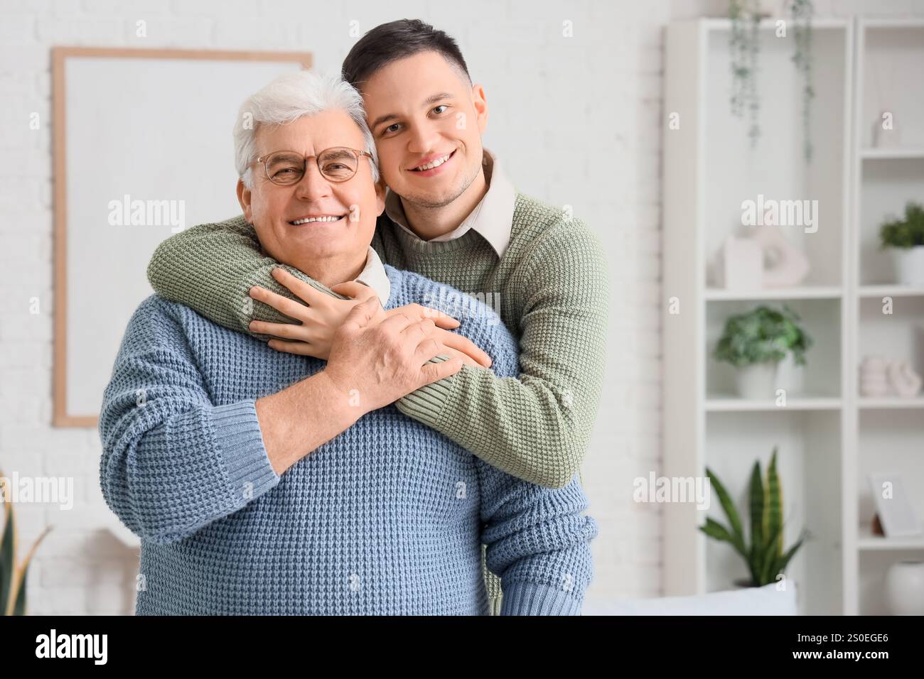 Young man hugging his father at home Stock Photo - Alamy