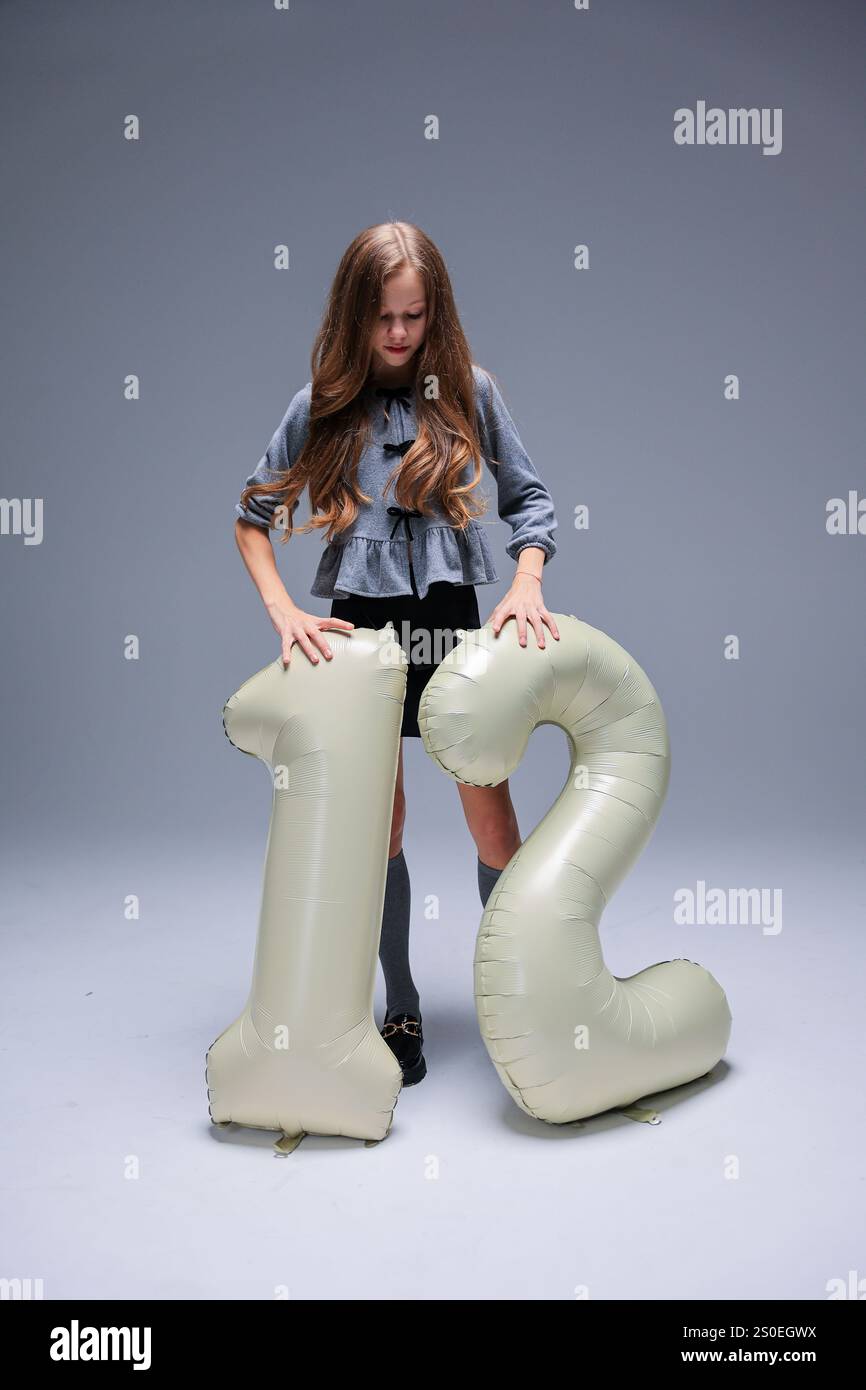 A playful girl poses with large inflatable numbers in a stylish and ...