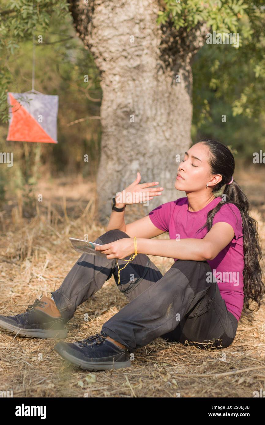 Orienteering athlete taking a break for hot under a checkpoint tree ...