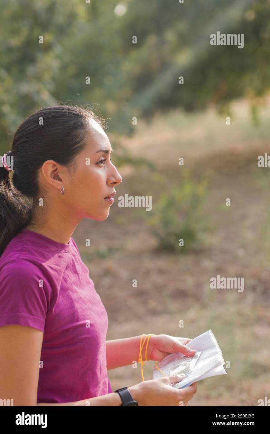 Young latin woman navigating with map and compass during orienteering ...