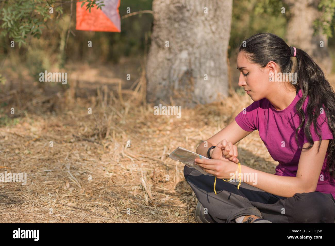 Woman orienteering in the woods checking time and map. Latin young ...
