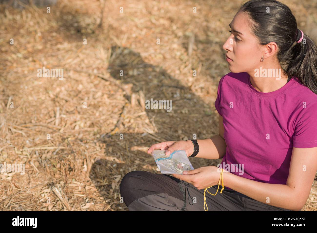 Latin woman orienteering using map and compass in dry landscape. Latin ...