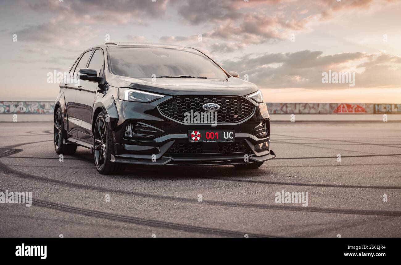 Black Ford Edge ST in huge parking lot at sunset. Front three quarter ...