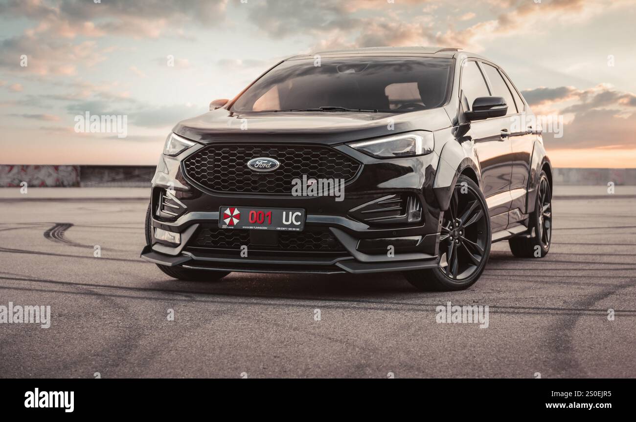 Black Ford Edge ST in huge parking lot at sunset. Front three quarter ...