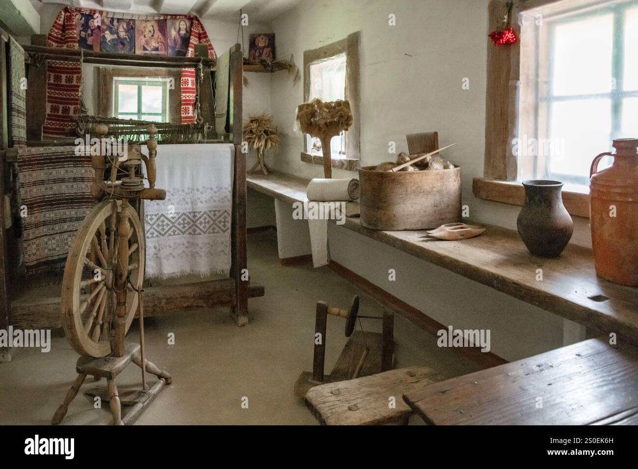 A room with a spinning wheel and a basket of dried flowers. The room is ...