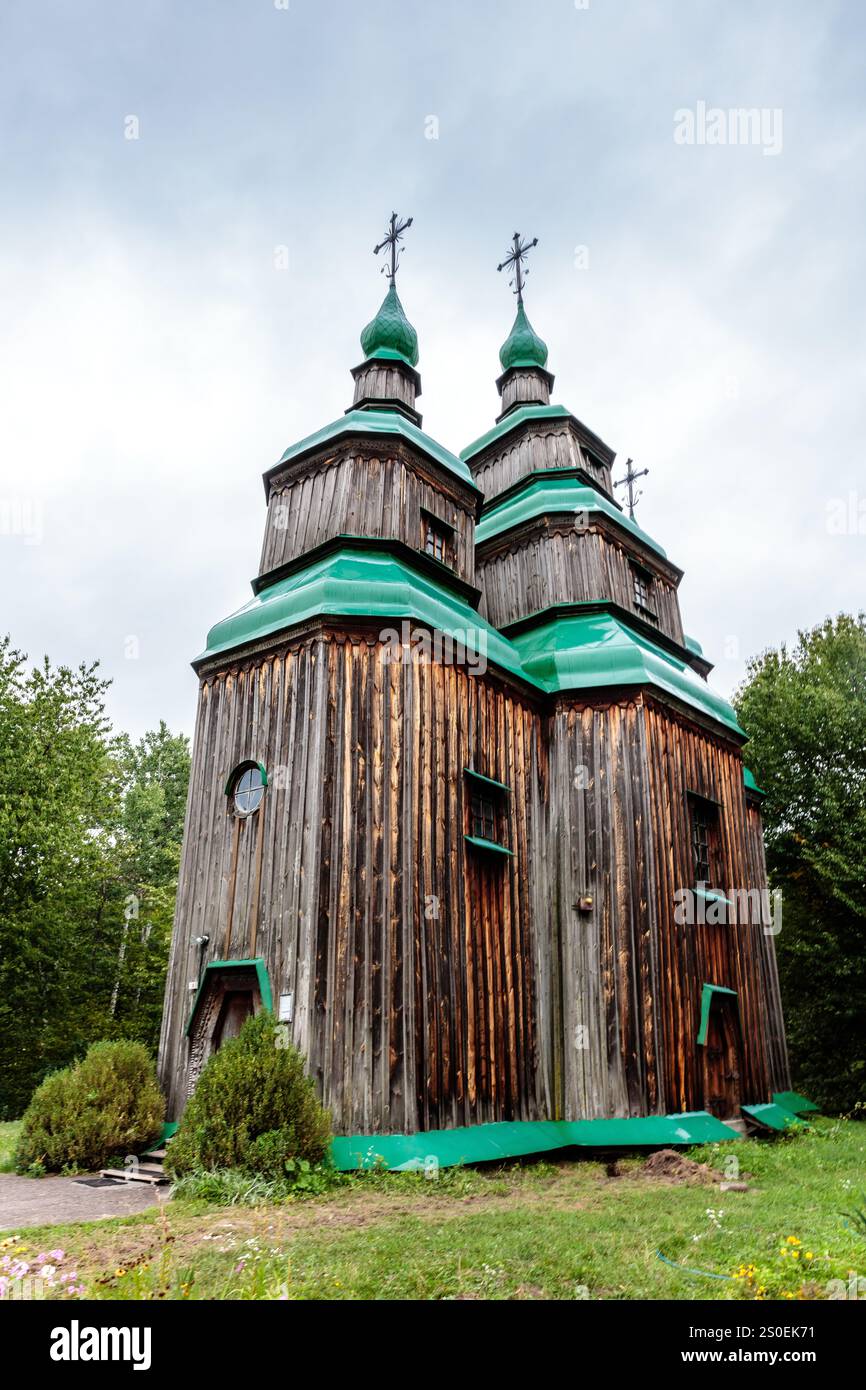 A large wooden church with two green domes on top. The church is ...