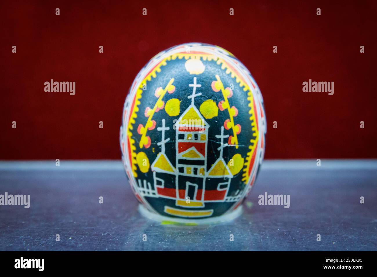 A small, painted egg with a church on it sits on a table. The egg is ...