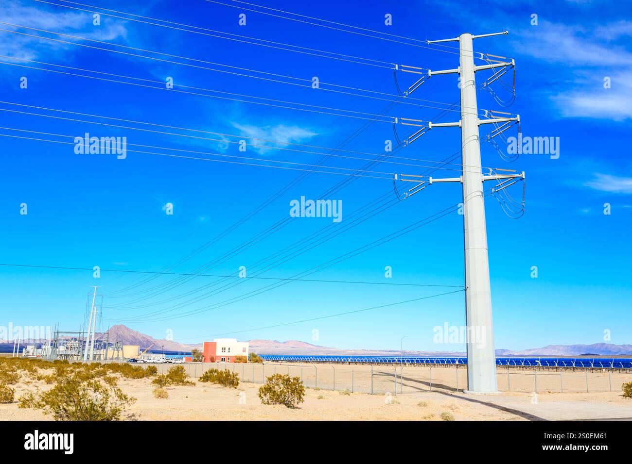 A tall power pole stands in the desert, with a clear blue sky above ...