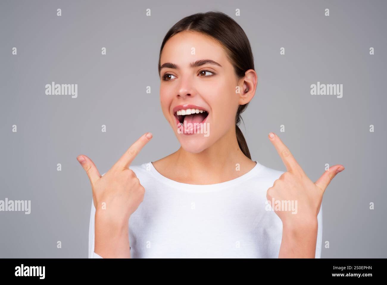 Young smiling happy woman point index fingers on opened mouth teeth ...