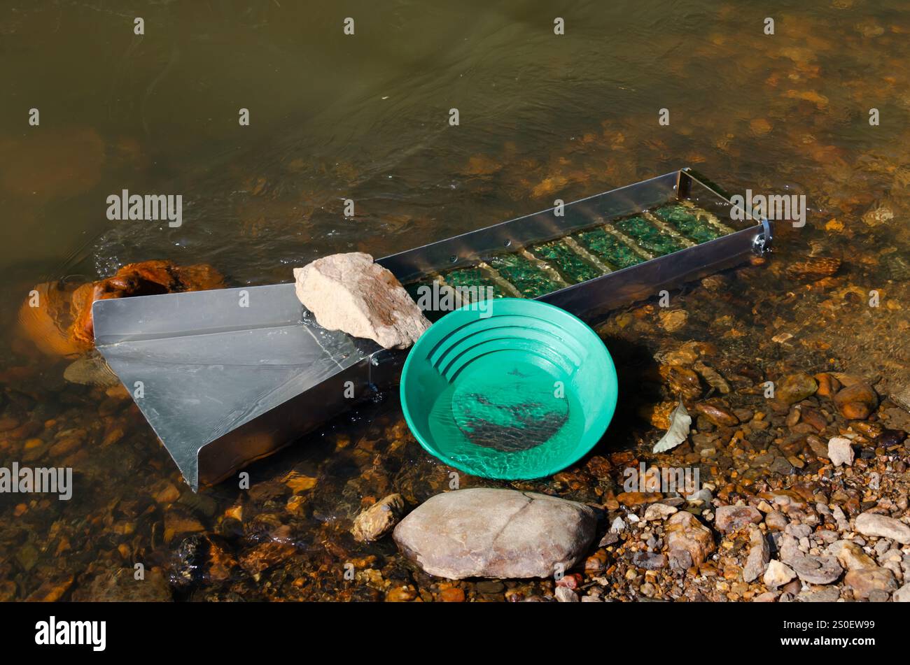 Gold panning and mining in riverbed. prospecting for gold using sluice ...