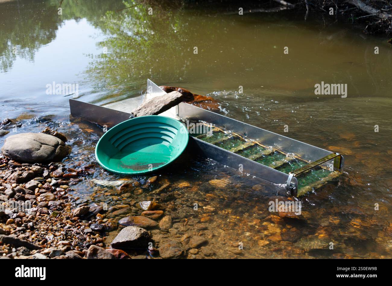 Gold panning and mining in riverbed. prospecting for gold using sluice box and gold pan. Gold ...