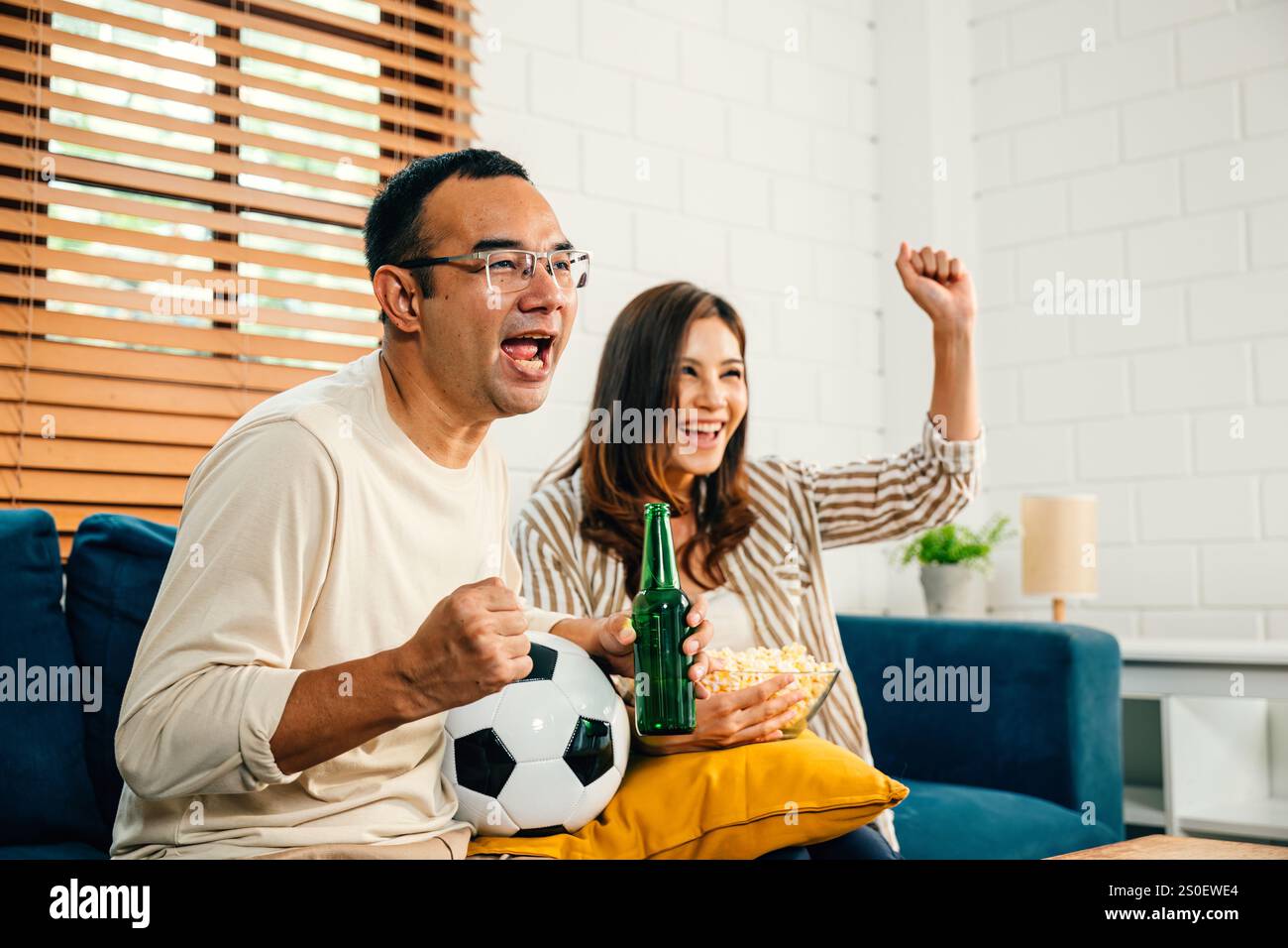 Excited young couple celebrates victory while watching TV their cheers ...
