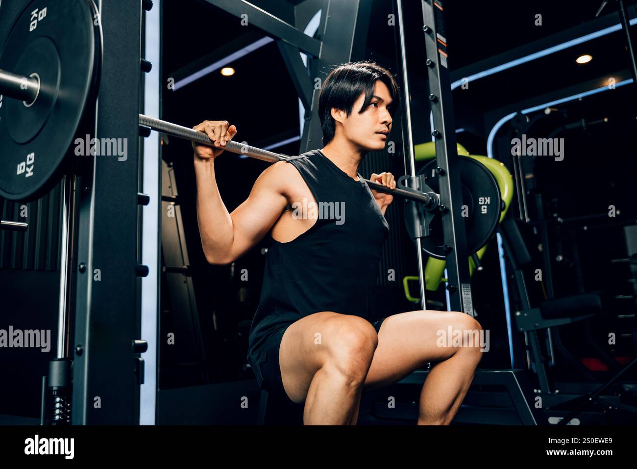 Asian muscular man guy performing a squat exercise legs heavy weights ...