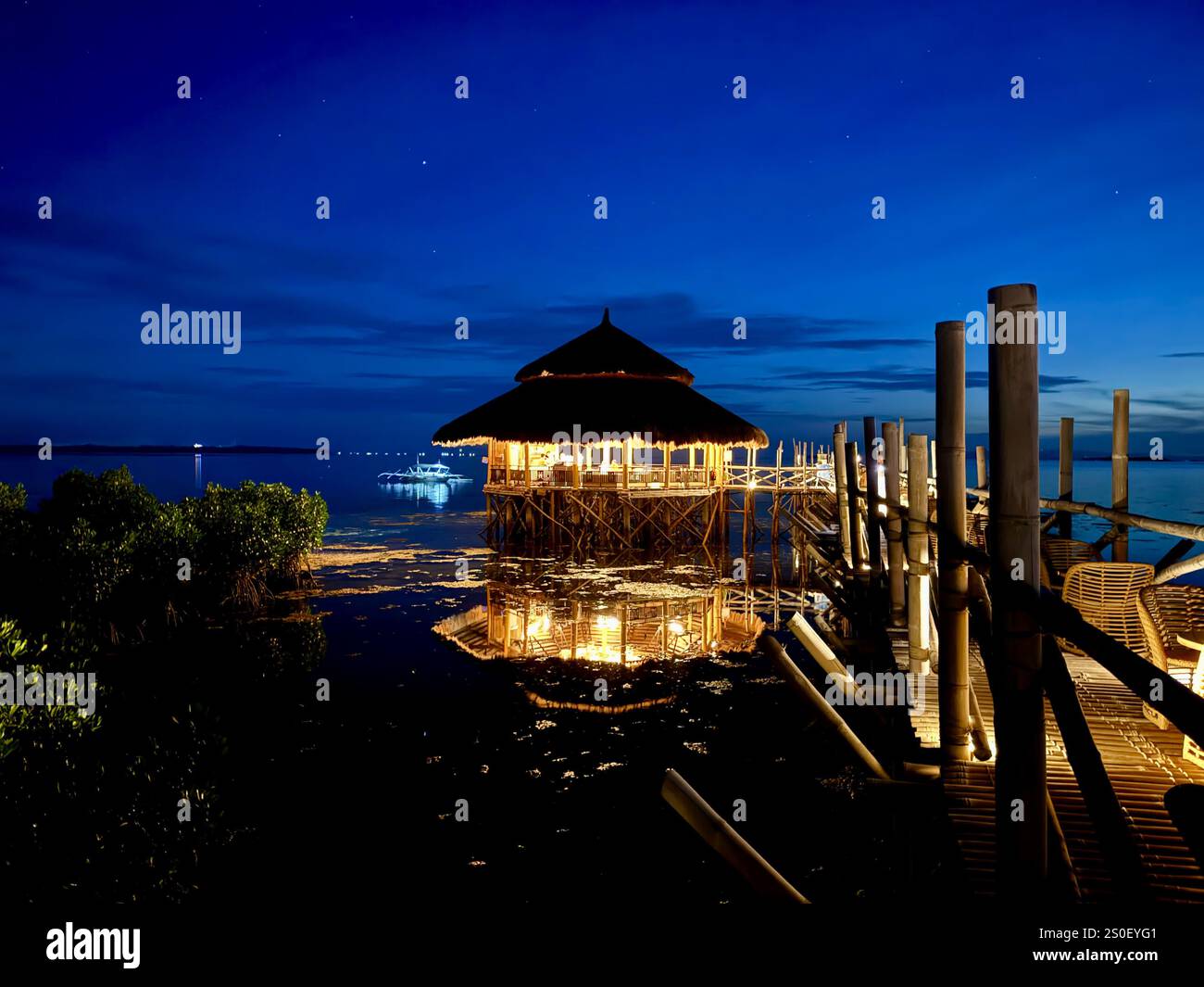 Tropical Overwater Restaurant at Night with Wooden Walkway and Bright ...