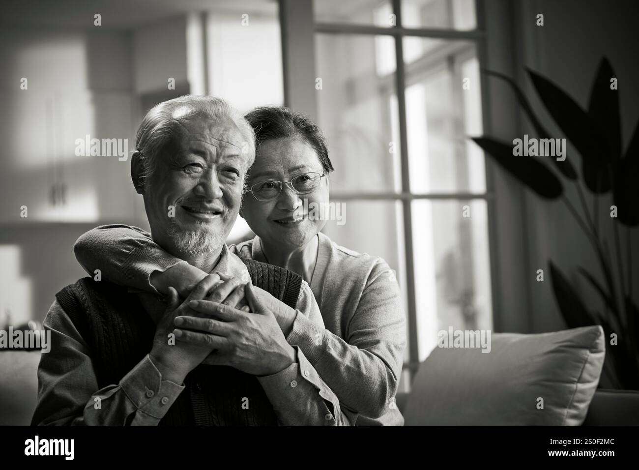 black and white portrait of happy loving senior asian couple sitting on couch at home Stock ...