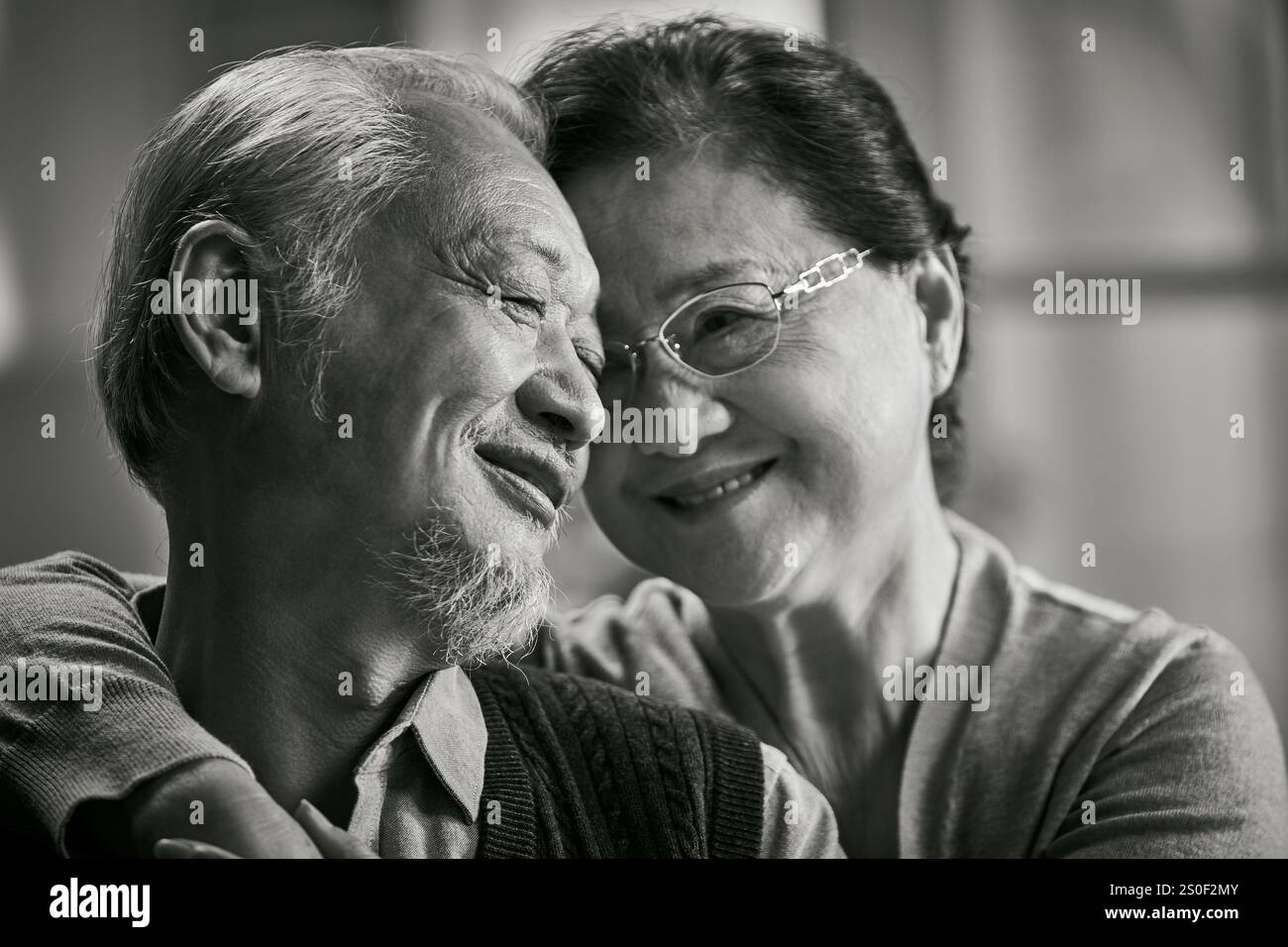 black and white portrait of happy loving senior asian couple sitting on couch at home Stock ...