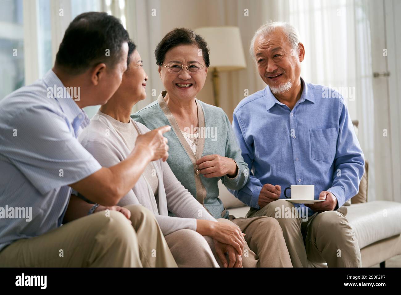 two happy senior asian couples sitting on couch at home having a pleasant conversation Stock ...