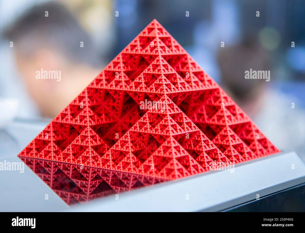 Art object printed on 3D printer from red melted plastic close-up. Model of pyramid created on ...