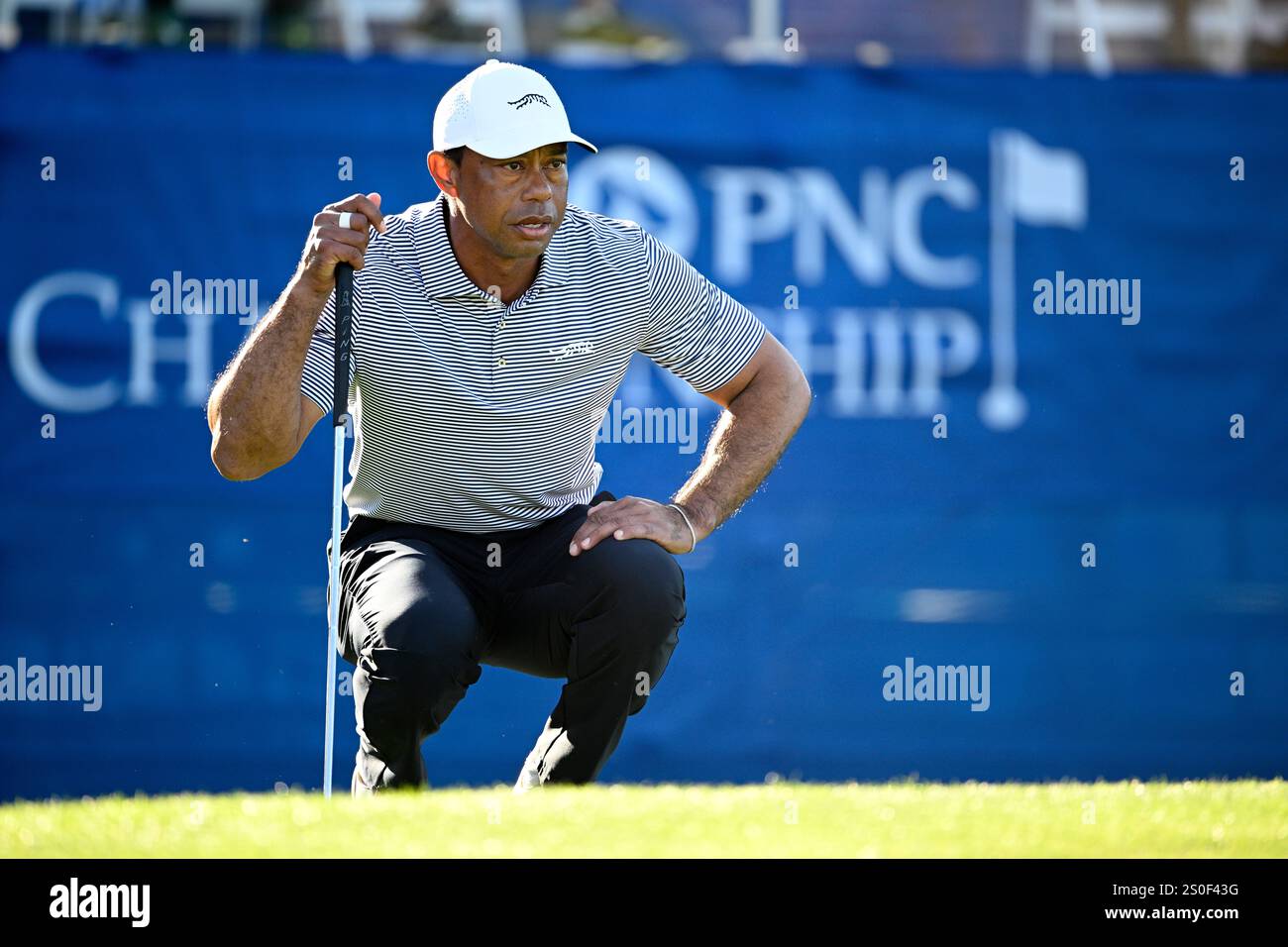 Tiger Woods lines up a putt on the 18th green during the first round of ...
