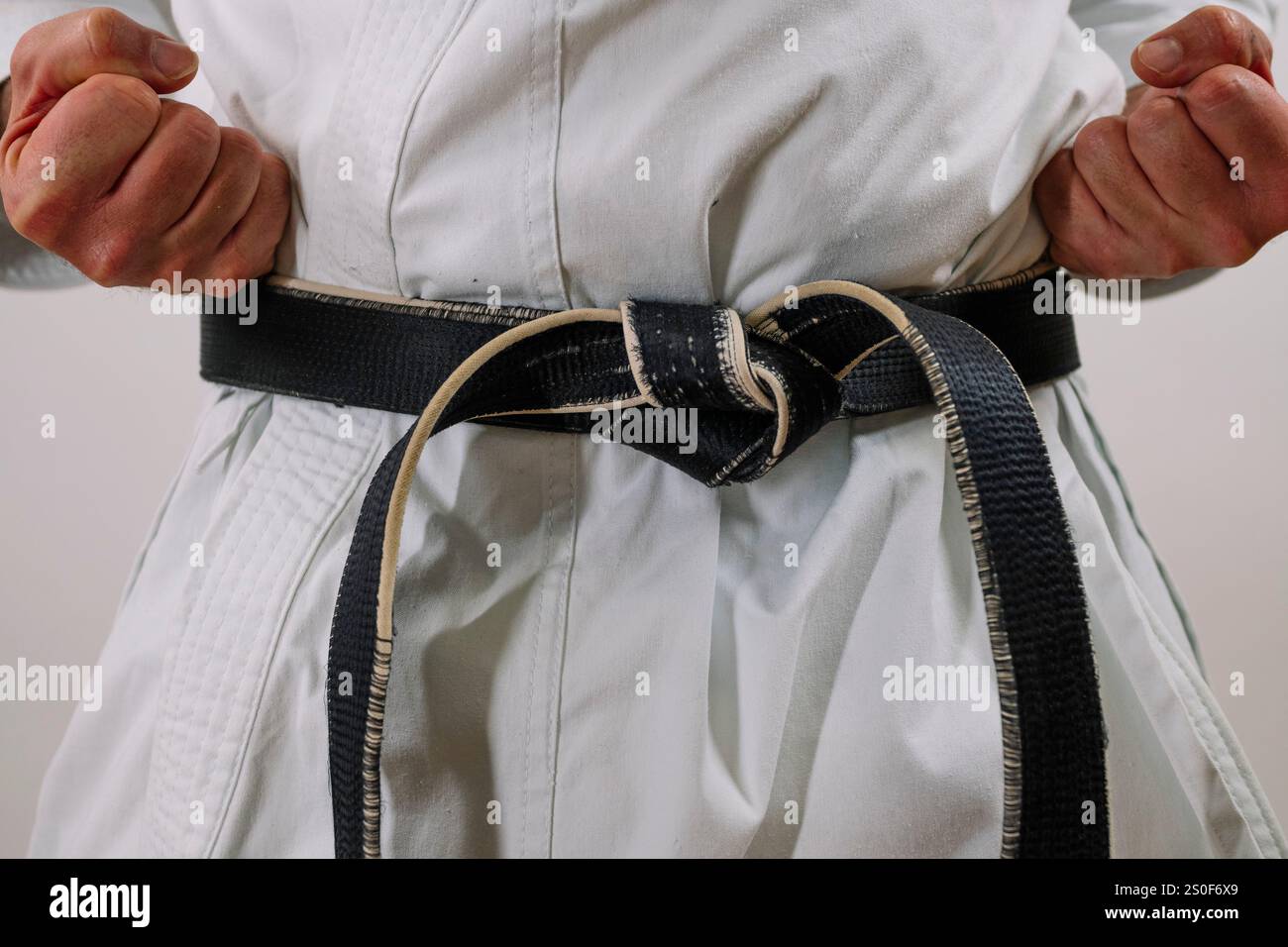 Black belt tied around a white gi Stock Photo - Alamy