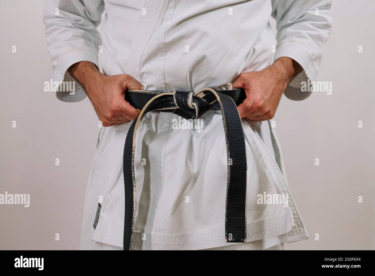 Black belt tied around a white gi Stock Photo - Alamy