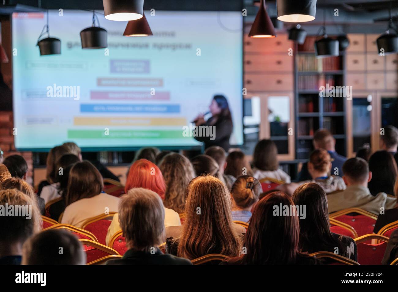 Large audience attending a seminar with presenter speaking on stage and ...