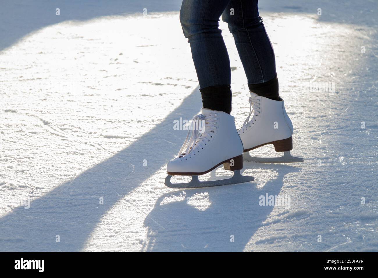 Legs of a young woman glide gracefully across the icy surface of an ...