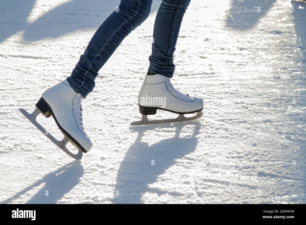 The legs of a young woman glide gracefully across the icy surface of an ...