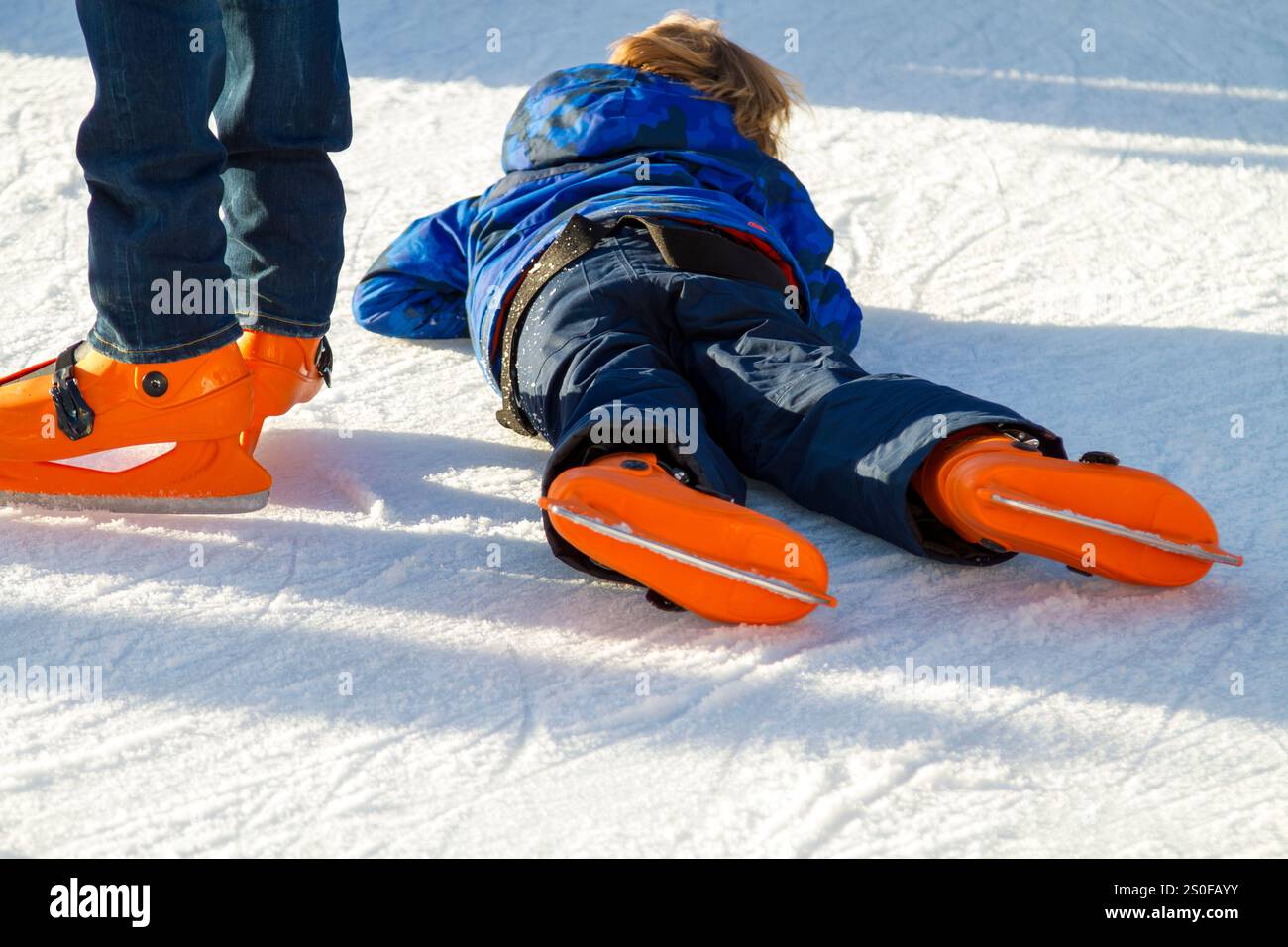 Child slips and falls on the icy surface of an outdoor ice rink during ...