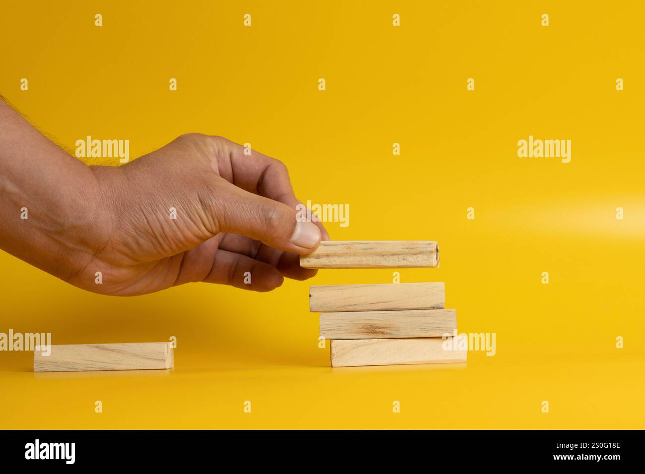 An image featuring a man placing a wooden Jenga blocks on three wooden ...