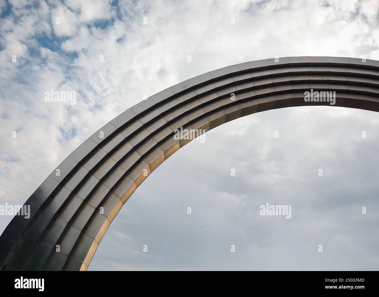 Looking up at metal arch in cloudy sky. High-tech titanium curve bridge ...