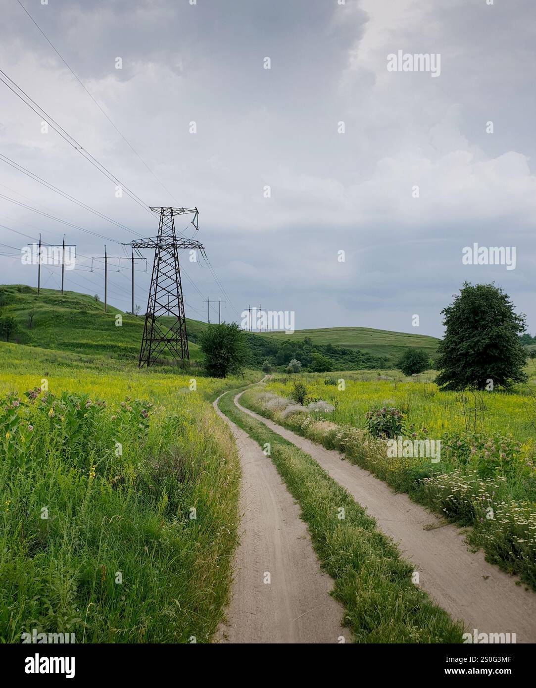 Dirt road amid hilly terrain, few transmission towers on top of the ...