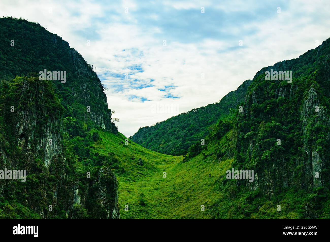 green passage between two mountain in cloudy sky Stock Photo - Alamy
