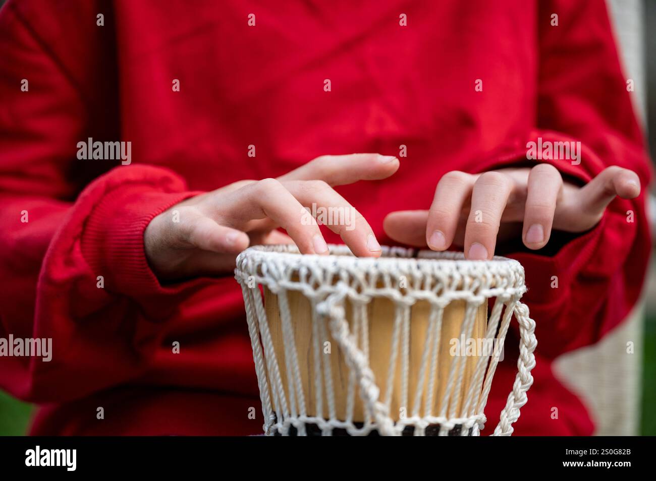 Closeup of hands tapping on a small djembe drum, with the player ...