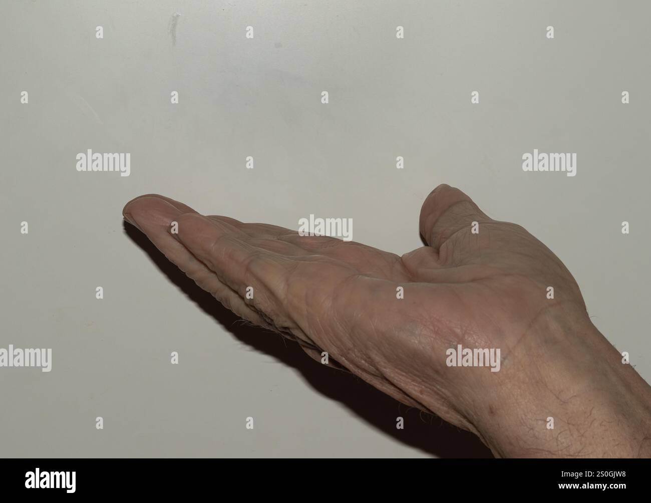 Open palm of an elderly hand against a plain background, conveying an ...