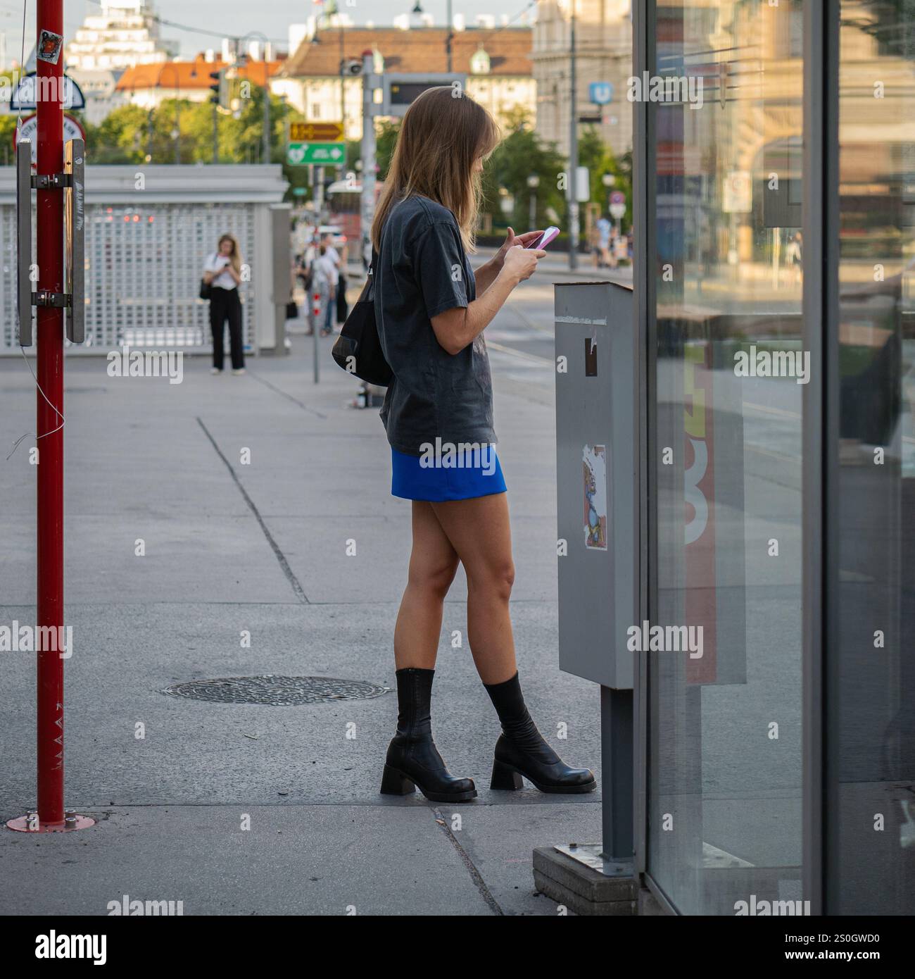 Pretty Girl in Miniskirt and Boots Waiting for Bus on Street Looking at ...