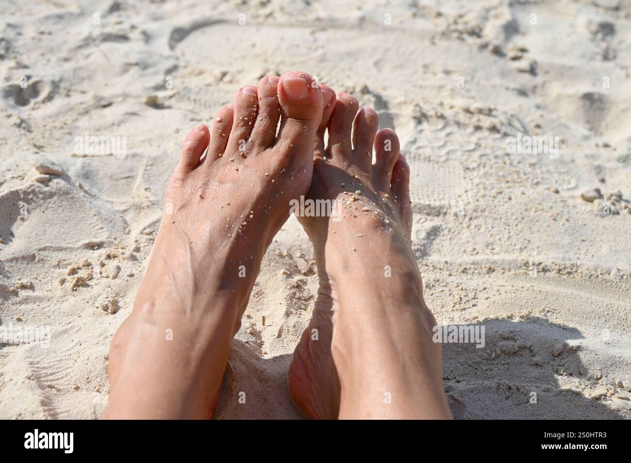 Human feet on sunlit beach sand background Stock Photo - Alamy