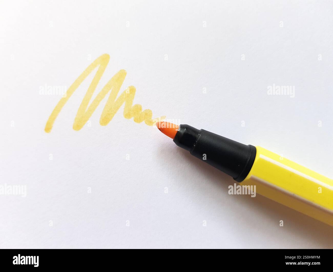 Close up of a yellow felt tip pen and scribble on a white background ...