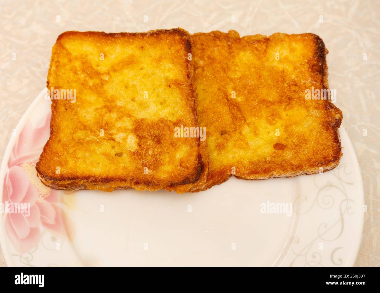Two slices of perfectly toasted bread sit on an elegant plate. The ...