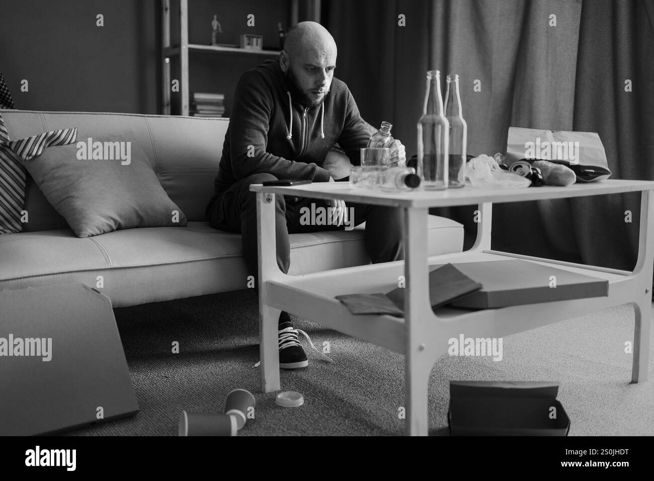 adult man is sitting home next to the table in his hands with bottle of ...