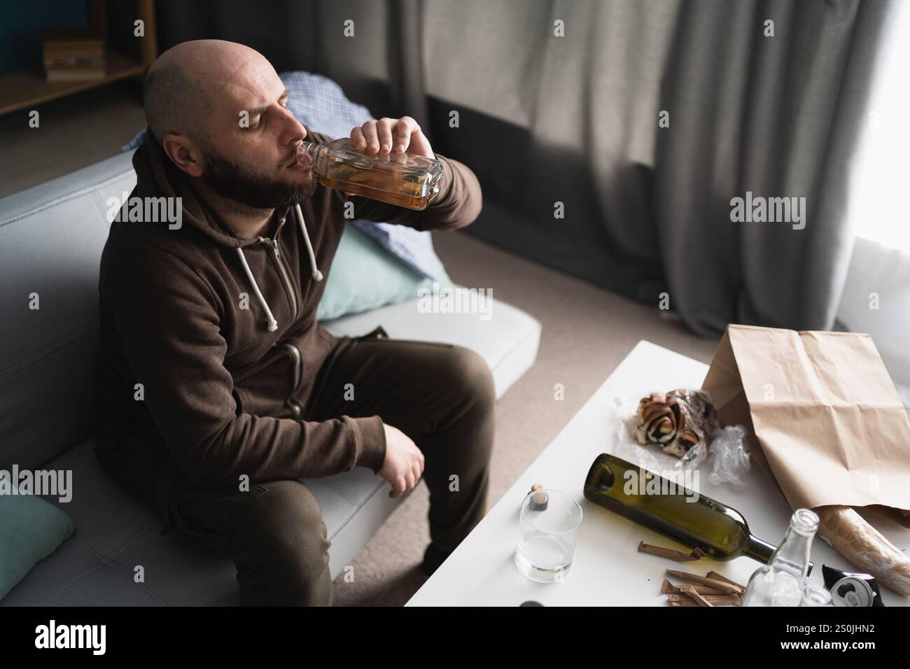 adult sad man drinking alcohol alone at home. holding bottle of alcohol ...