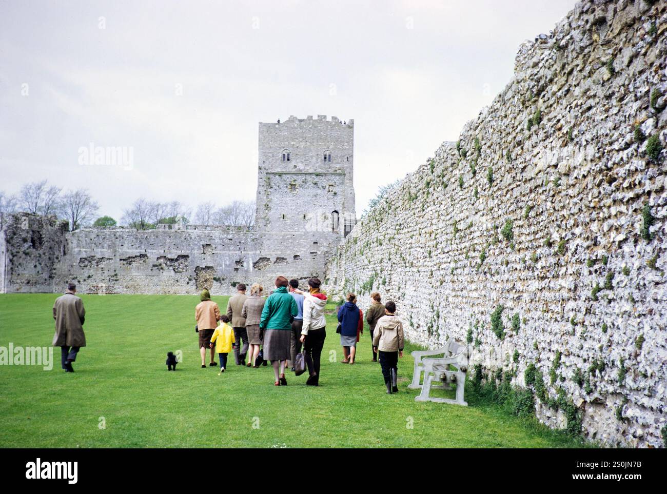 People walking by Roman walls of Portchester Castle, Hampshire, England ...