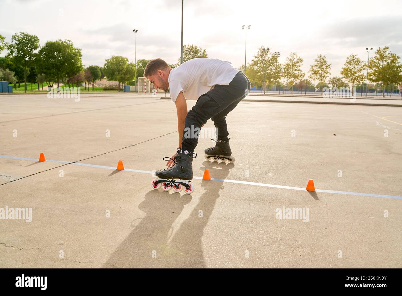 Man adjusting cones while rollerblading in an outdoor park Stock Photo ...