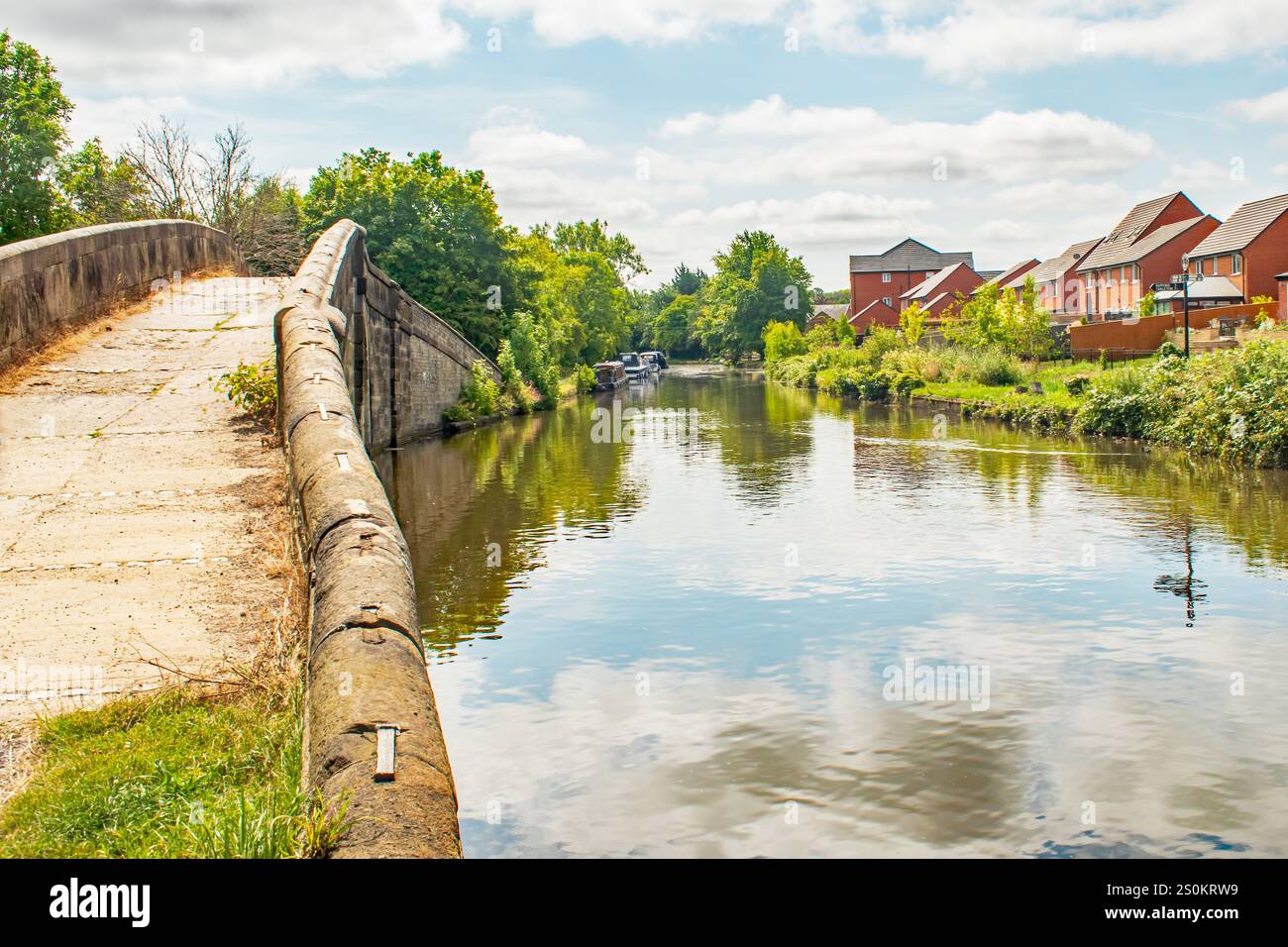 An old stone bridge crosses along the Leeds-Liverpool canal on a bright ...