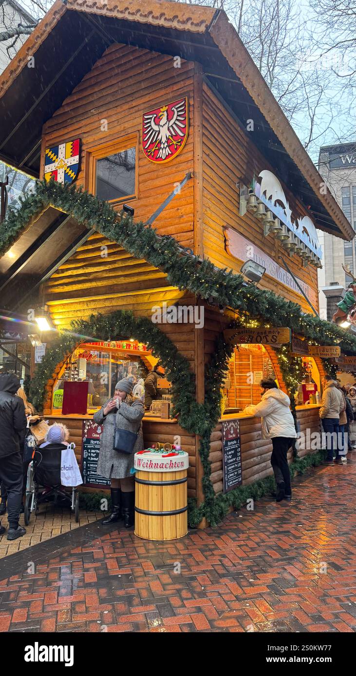 A snow-dusted wooden Christmas market stall, adorned with garlands and ...
